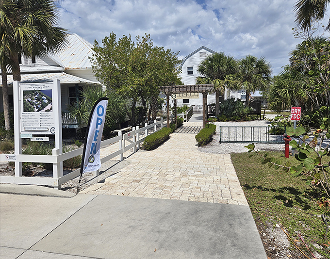 The welcoming pathway lined with native plants sets the stage for time travel, inviting curious souls into Sanibel's storied past.