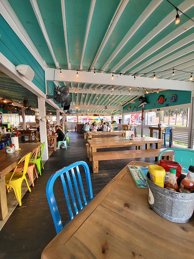 Rustic wooden tables beneath turquoise rafters strung with twinkling lights create the perfect backdrop for seafood feasts and vacation memories.