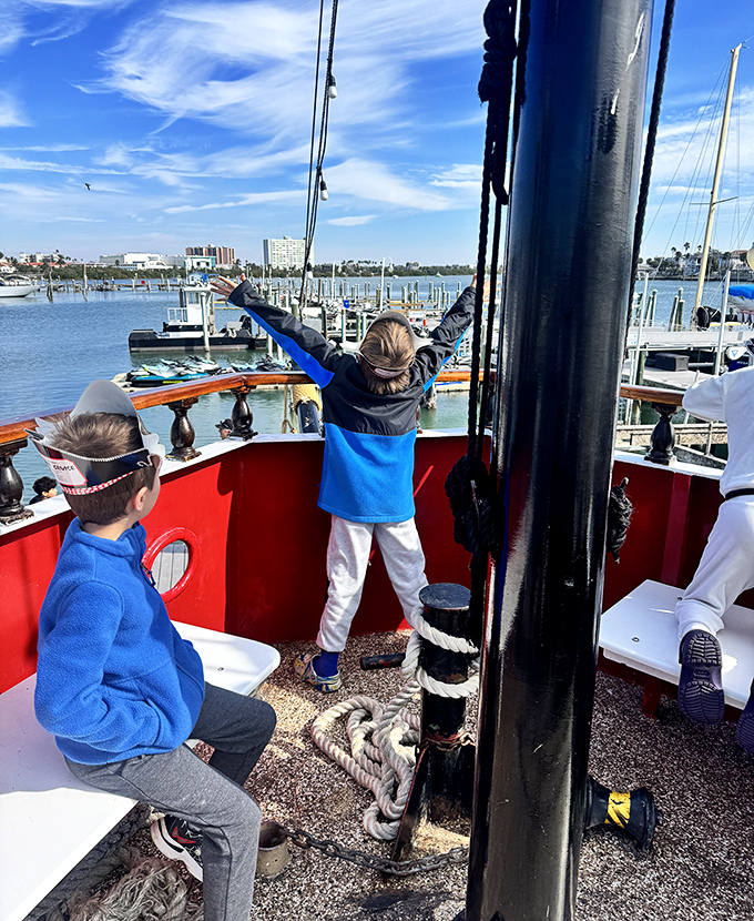 Young adventurers embrace their inner buccaneers, arms raised in triumph as they claim the bow as their lookout post.