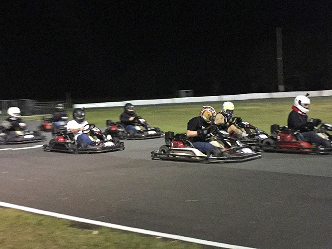Under the cover of darkness, racers battle for position while navigating the twisting half-mile track, their helmets gleaming under the floodlights.