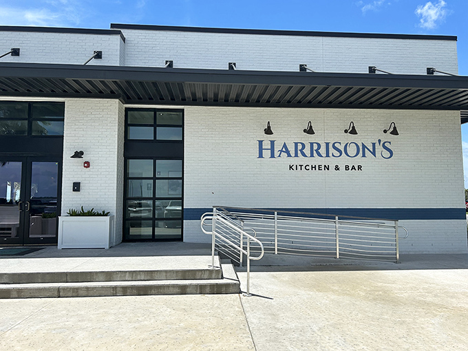Modern elegance meets waterfront dining at Harrison's Kitchen & Bar. The clean white brick exterior hints at the upscale oyster experience waiting inside.