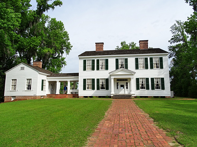The historic white plantation house at Torreya State Park stands proudly against a backdrop of green lawn and towering trees.