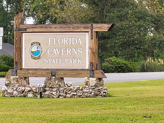 The welcoming sign at Florida Caverns State Park stands amid tropical foliage, inviting explorers to discover Florida's underground wonders.