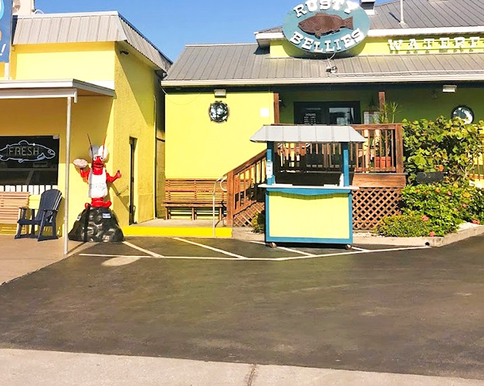 The whimsical lobster statue welcomes seafood lovers to Rusty Bellies, where waterfront dining means watching your dinner arrive by boat.