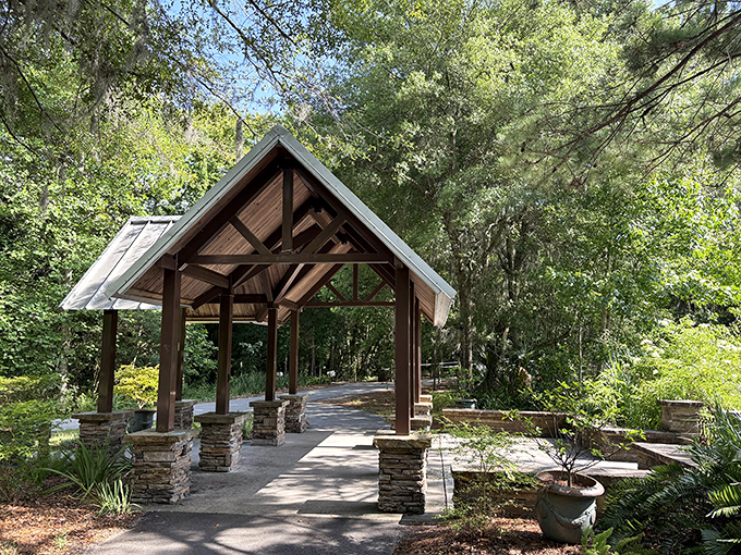 The covered walkway stands like a rustic cathedral of nature, inviting visitors to pass through its wooden arches into green serenity.