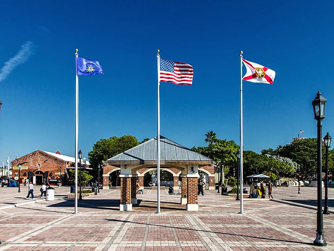 Three flags wave above the garden pavilion, representing Key West's layered identity and complicated past in simple, fluttering fabric.