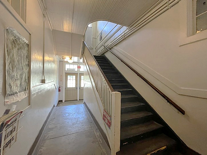 The pristine white hallway and wooden staircase invite visitors to explore both floors of this lovingly maintained historic building.
