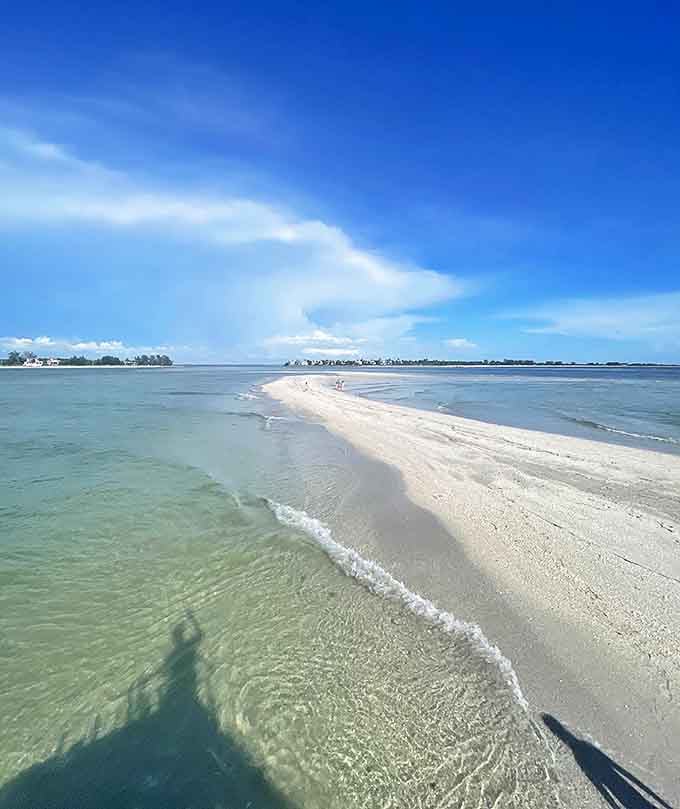 A narrow sandbar stretches into the crystal-clear turquoise waters, inviting you to wander along this pristine, secluded island shoreline.