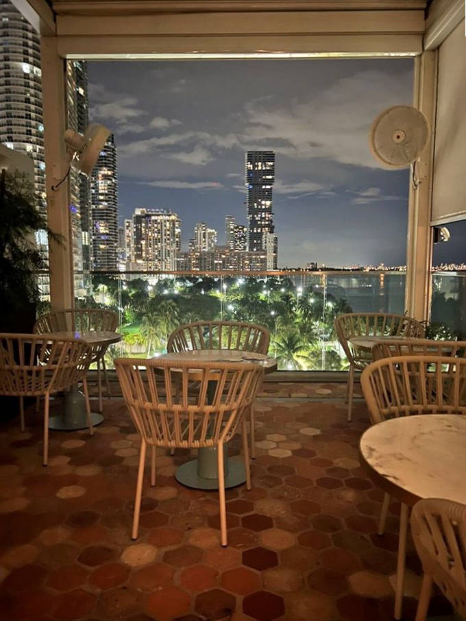 As night falls, Klaw's elegant table settings glow under soft lighting. The Miami skyline creates a dazzling backdrop for king crab and premium steaks.