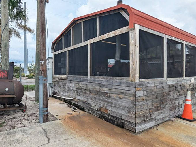 The outdoor seating area at Smokin' Jim's features simple white chairs under a wooden shelter, perfect for enjoying smoky delights in the Florida air.