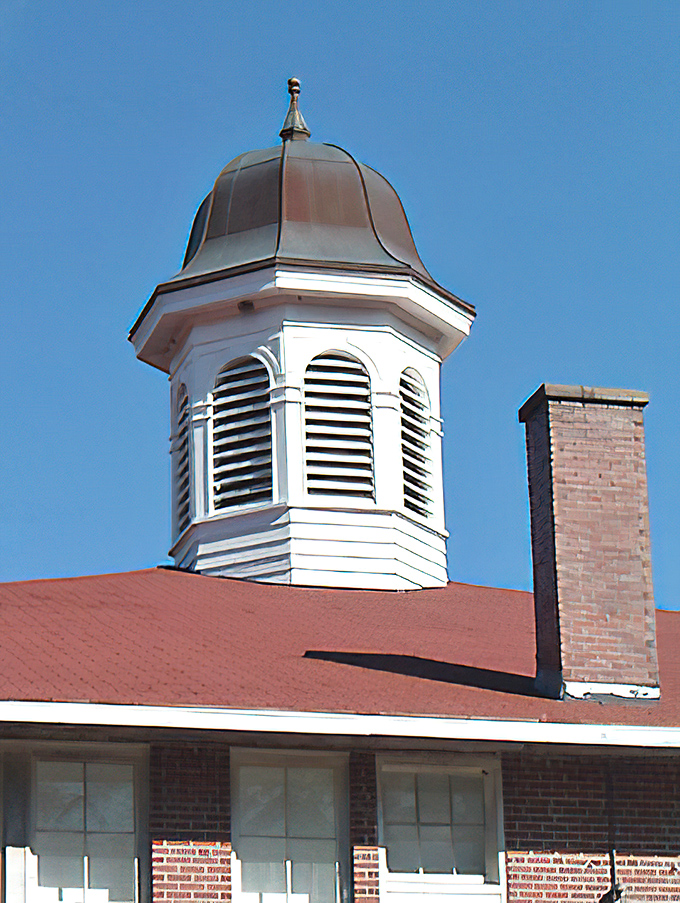 The schoolhouse's copper-topped cupola gleams against the Florida sky, serving as both architectural flourish and community landmark.