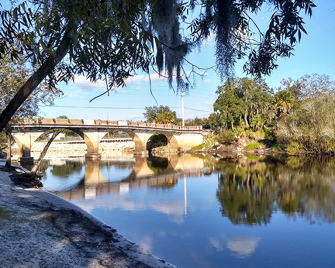 The historic Peace River Bridge reflects in calm waters below, a postcard-perfect scene where Spanish moss and Florida sunshine create nature's own antique filter.