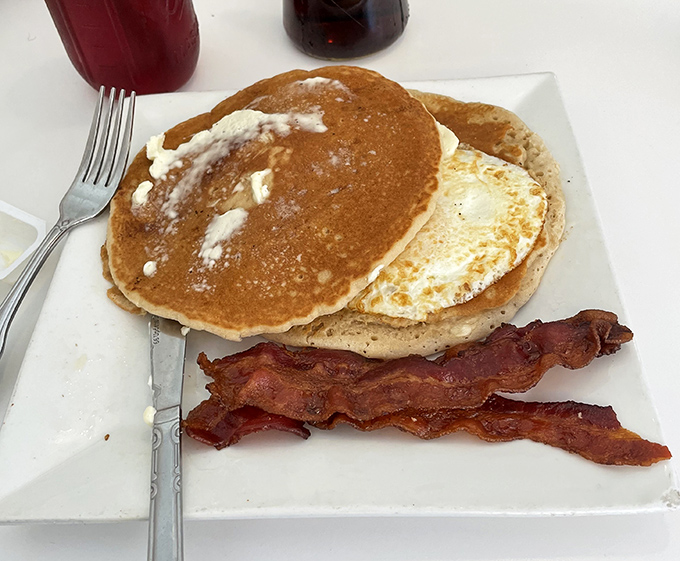 Pancakes so perfectly golden they belong in Fort Knox, paired with bacon that's achieved that magical balance between crisp and chewy.