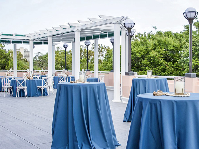 Blue-draped tables await beneath a pristine pergola, where Florida's gentle breezes turn ordinary gatherings into memorable celebrations.