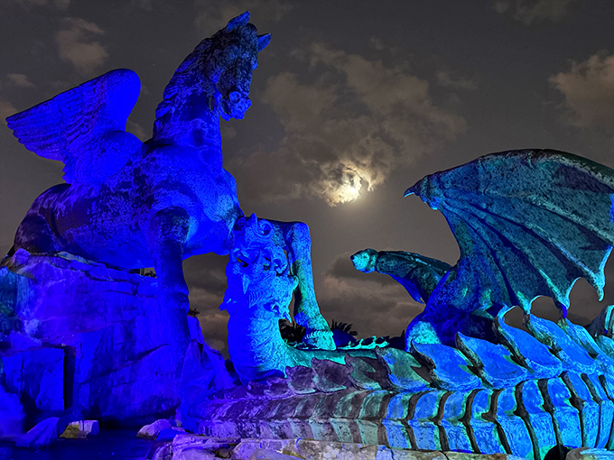 Under moonlight's spell, the statue transforms – bathed in ethereal blue illumination that turns bronze to magic.