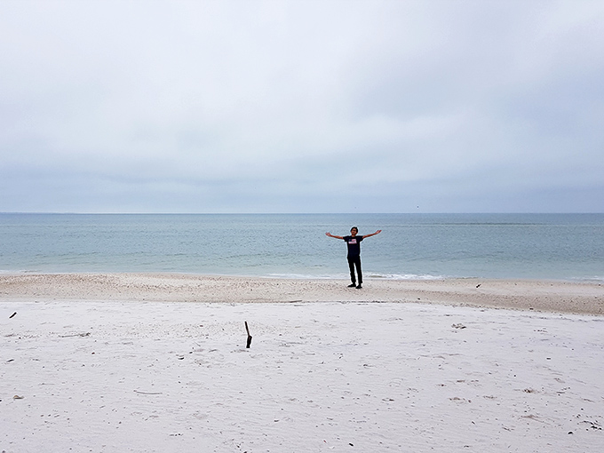 A solitary figure embraces the vastness of Crooked Island Beach, where personal space isn't just available &ndash; it's practically mandatory.