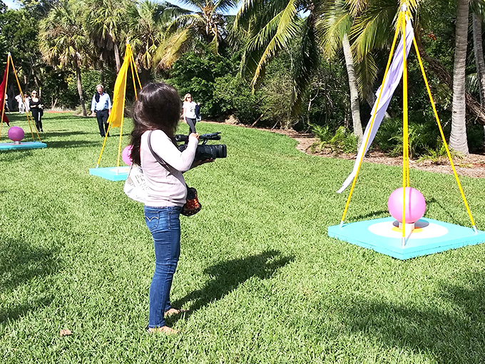 Visitors explore interactive art installations on the great lawn, where colorful suspended spheres contrast beautifully against the manicured green space.