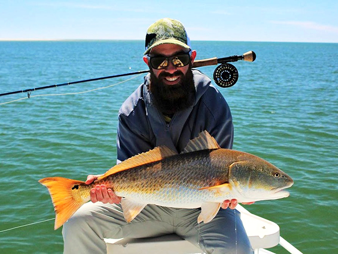"Just another terrible day fishing in paradise," jokes this angler, proudly displaying a magnificent redfish caught in St. Joseph Bay's fertile waters.