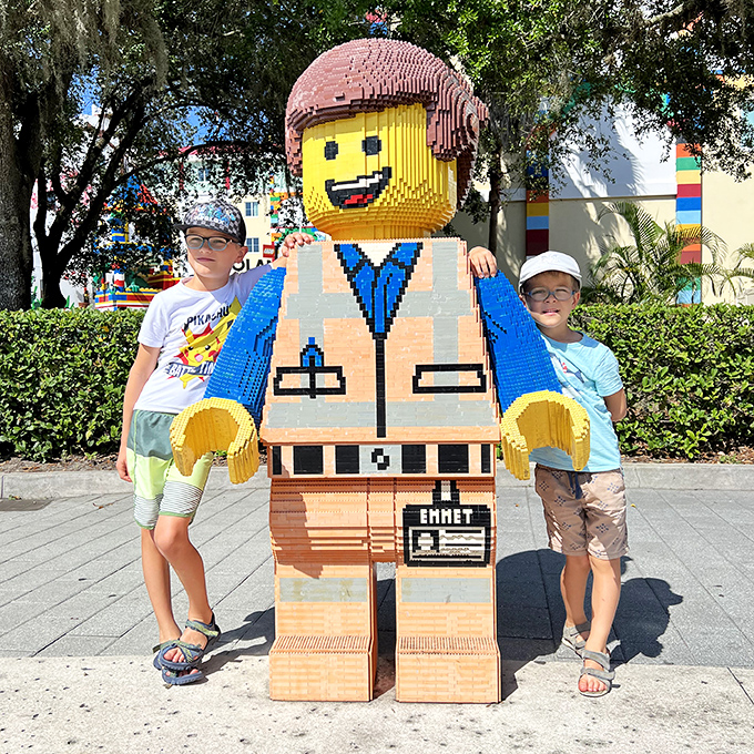 Young adventurers pose with an oversized LEGO Emmet figure, their expressions capturing the magic of seeing favorite characters brought to life.