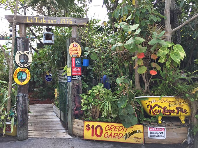 Le Tub's weathered entrance, adorned with quirky signs and lush greenery, promises Florida's most famous burgers hidden behind this unassuming facade.