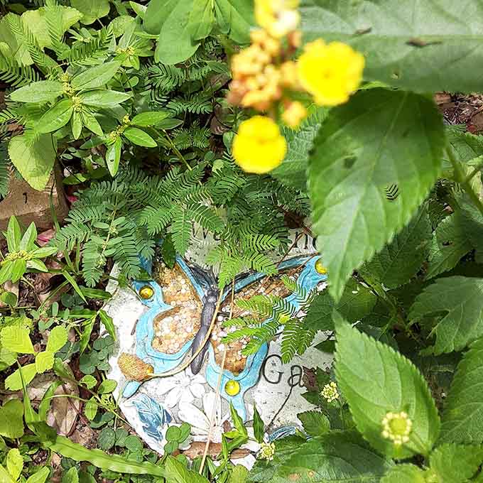 Garden art meets nature as decorative stepping stones guide visitors through this thoughtfully designed butterfly habitat.