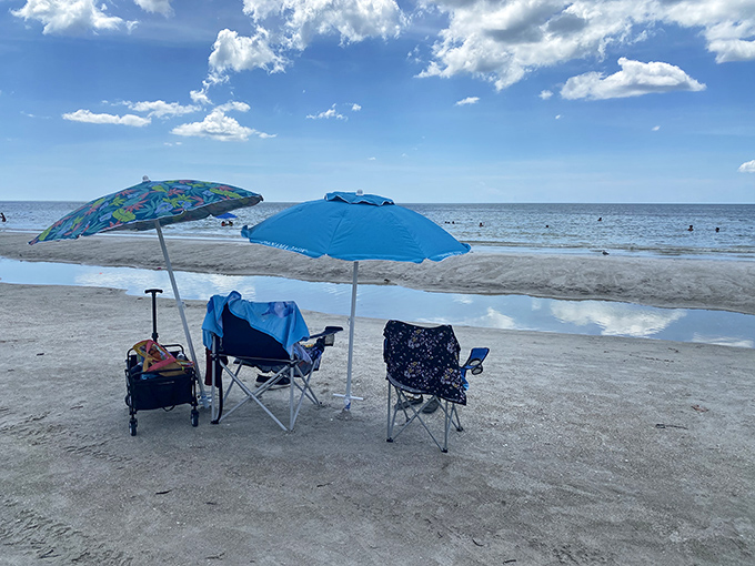 Beach day perfection captured: colorful umbrellas standing guard over empty chairs waiting for their sun-soaked occupants to return.