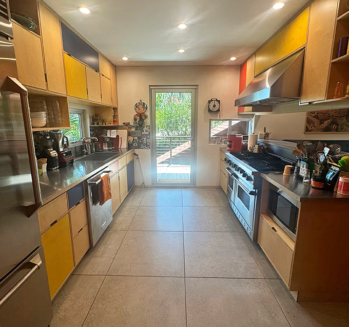 Cooking becomes performance art in this galley kitchen where colorful cabinets and professional-grade appliances make meal prep feel like a Food Network special.
