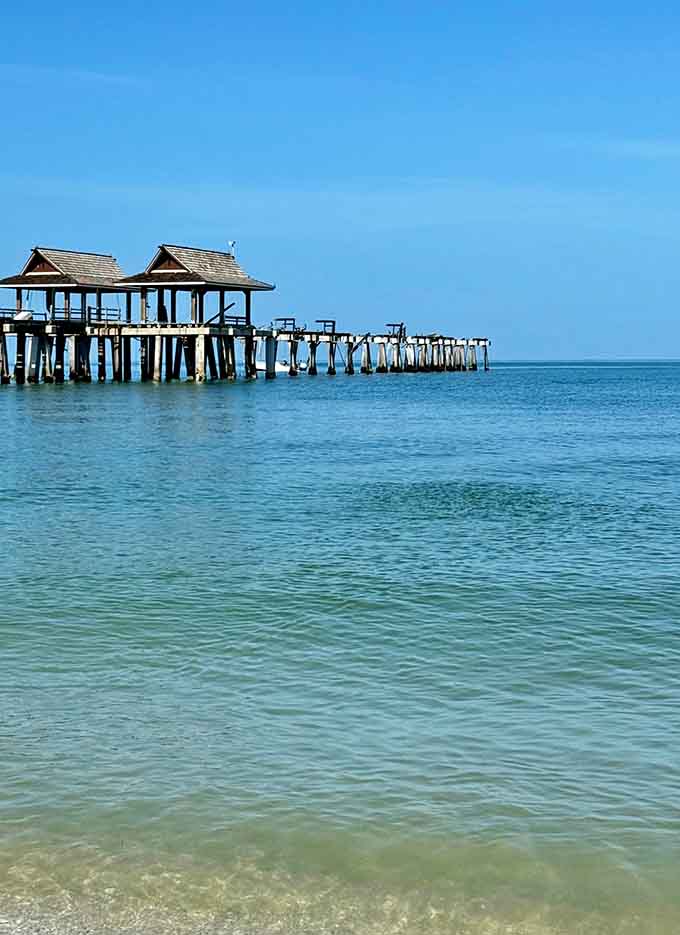 Naples Pier's distinctive covered structures stretch into crystal-clear Gulf waters that shimmer in shades of blue.