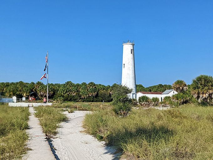The simple white tower of Egmont Key Light stands beside its brick keeper's house, a peaceful scene that transports visitors back to a simpler time.