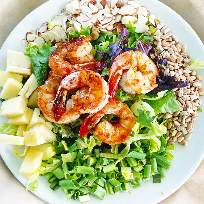 A garden party on a plate, where plump shrimp mingle with greens, nuts, and pineapple chunks in perfect harmony.