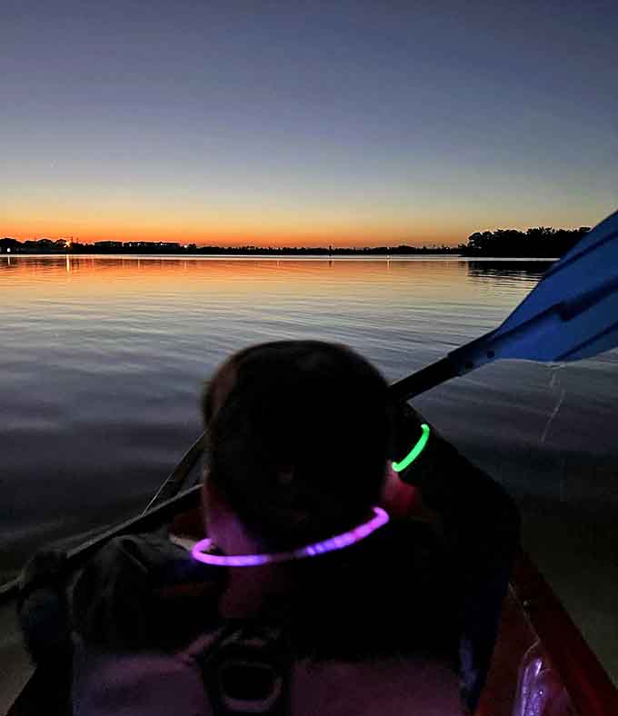 Sunset transitions to adventure as paddlers equipped with colorful glow sticks prepare for nature's light show beneath the darkening sky.