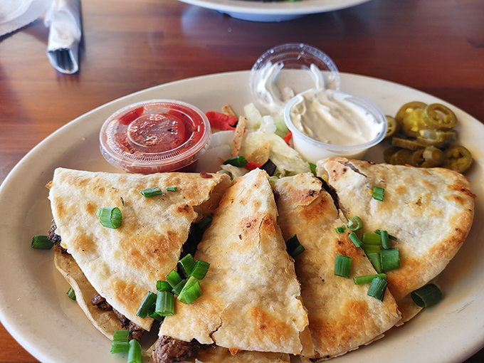 Golden-brown quesadillas arrive perfectly crisped, with each triangular slice revealing a treasure trove of melted cheese and savory fillings inside.