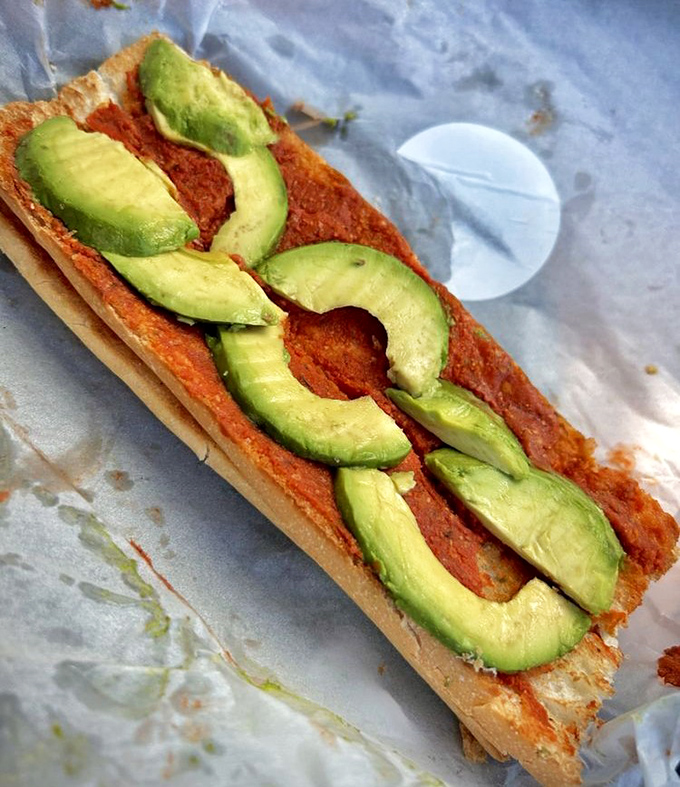 Avocado toast gets a vibrant makeover with creamy slices atop a canvas of bright red sauce &ndash; proof that simple ingredients can create extraordinary flavors.