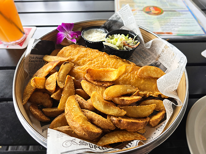 Fish and chips that demand to be photographed first, with that purple orchid adding tropical flair to this pub classic.