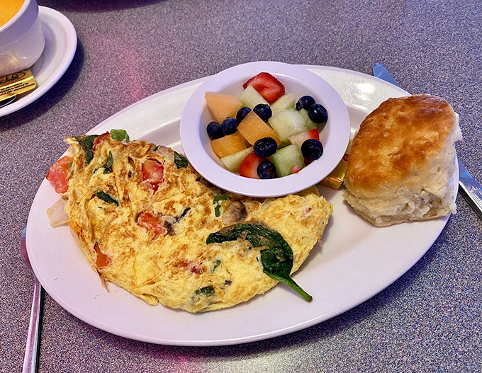 An omelet that defies the laws of egg physics, somehow containing a garden of vegetables and cheese while maintaining its structural integrity.