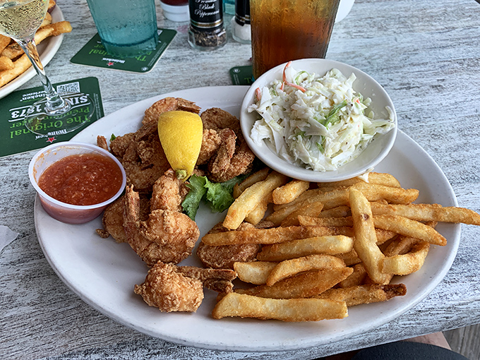 Golden-brown shrimp with crispy fries and creamy coleslaw – comfort food elevated by that ocean breeze.