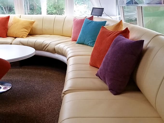 That curved sofa with its cheerful pillows proves sustainable living spaces can be stylish, comfortable, and perfect for community gatherings.