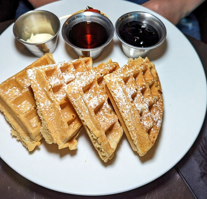 Golden Belgian waffles dusted with powdered sugar, served with three dipping options that turn breakfast into an adventure of sweet possibilities.