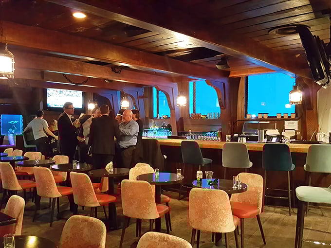 The elegant bar area at The Wreck offers comfortable seating where guests can sip cocktails while watching underwater performances through the aquarium windows.