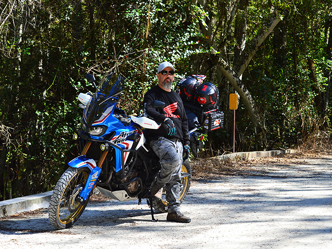 A modern explorer pauses his journey, his motorcycle a stark contrast to the timeless wilderness that has remained unchanged for centuries.