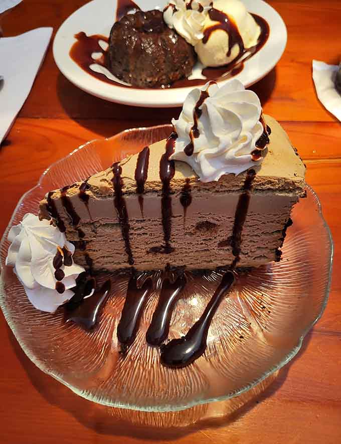 That towering slice of chocolate cake with whipped cream and chocolate drizzle is basically happiness on a plate, no exaggeration needed.