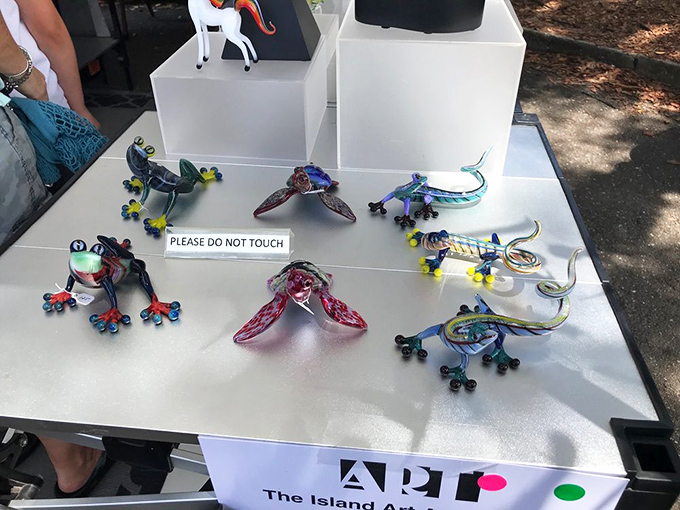 Whimsical glass frogs and lizards seem ready to leap from their display, showcasing the playful side of serious artistic talent.