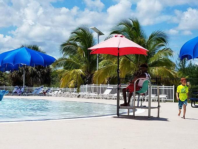 Lifeguards maintain vigilant watch over splashing visitors, somehow looking professional despite sitting in what's essentially a glorified high chair with an umbrella.