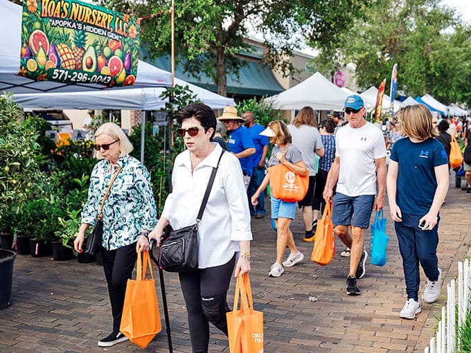 Crowds meander through the festival aisles, orange shopping bags in hand, evidence of successful plant acquisition missions already accomplished.