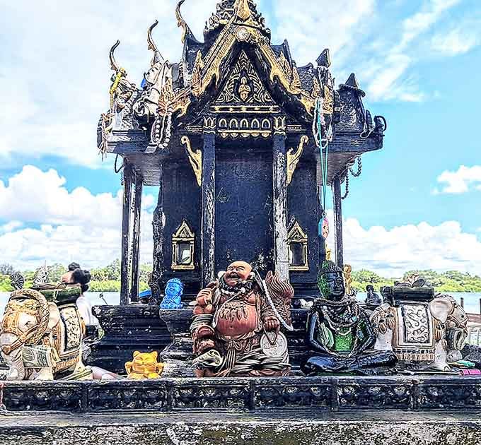 Traditional spirit houses like this ornate structure honor protective spirits in authentic Thai religious practice and architectural style.