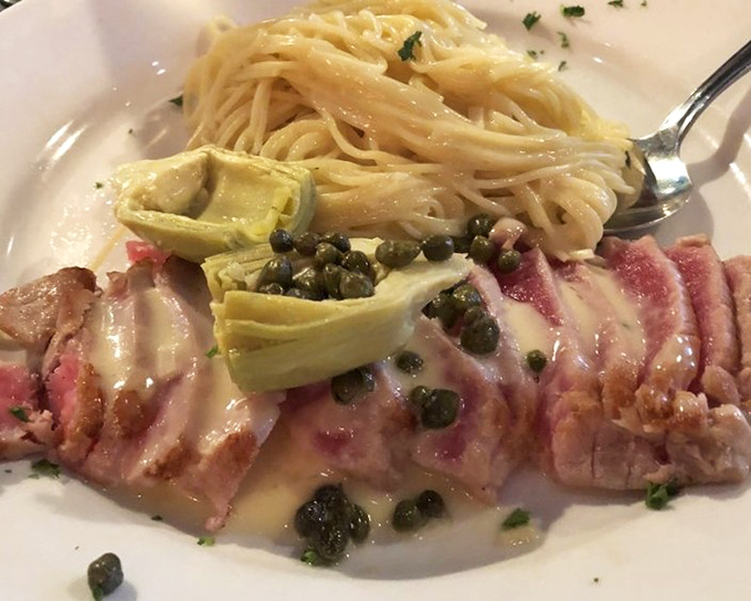Seared ahi tuna sliced to perfection with artichokes and capers, showing off that gorgeous pink center that makes seafood lovers weep with joy.