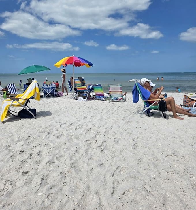 Beach umbrellas dot the shoreline like colorful mushrooms, each one marking someone's personal slice of paradise for the day.