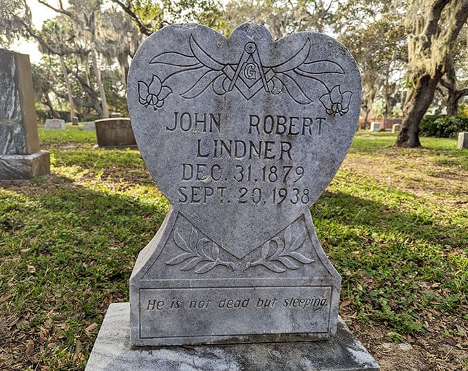 Heart-shaped monuments and Masonic symbols reveal the personal beliefs and affiliations that mattered to those who rest here beneath the oaks.