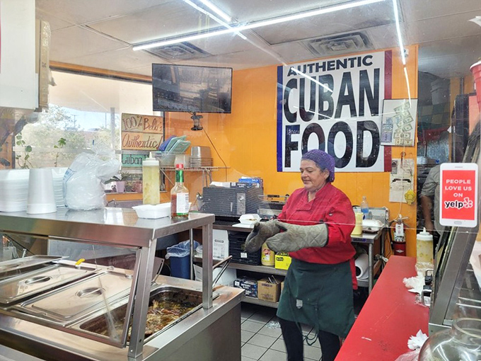 Behind the counter, where sandwich dreams come true. The bright "AUTHENTIC CUBAN FOOD" sign isn't just decoration – it's a promise.