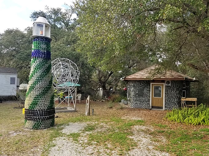 A whimsical lighthouse made entirely of bottles stands sentinel beside a small structure, both glittering with thousands of glass bottoms catching the Florida sunlight.
